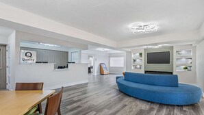 Um lobby moderno de hotel com balcão de recepção, um sofá azul e uma área de refeições.
