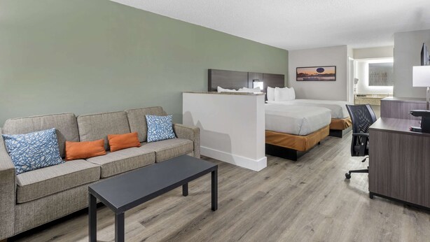 Quarto de hotel com sofá, cama, escrivaninha e cadeira.
