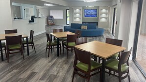 Espaço moderno e interno com área de jantar, um sofá azul e uma TV de tela plana.