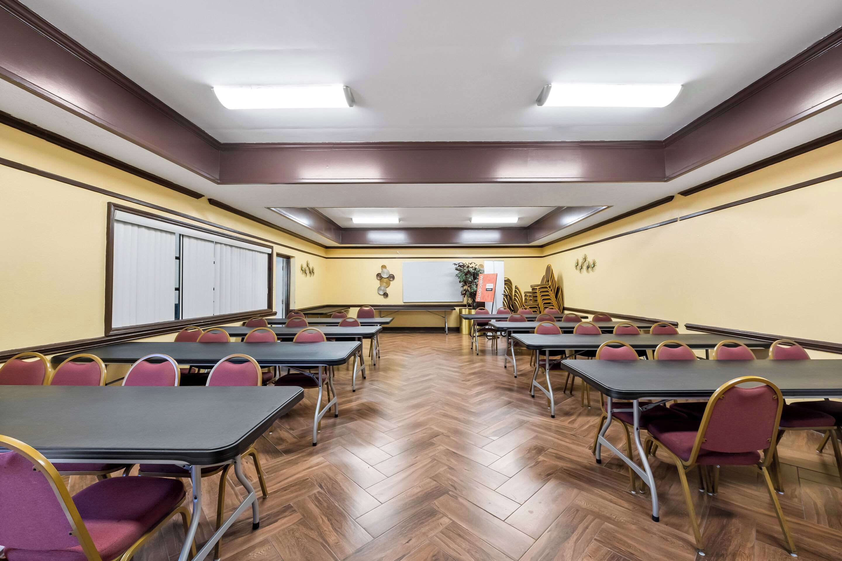 Uma sala de conferências com várias mesas e cadeiras, uma lousa e um projetor.