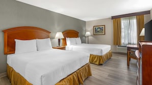 Quarto de hotel com duas camas, uma escrivaninha e uma cadeira.