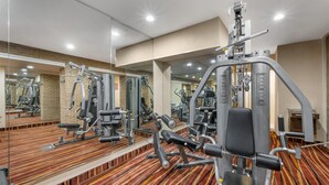 Uma academia com equipamentos de ginástica, espelhos e um carpete estampado.