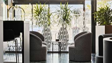 Um lobby moderno com divisória de vidro, área de estar e plantas em vasos.