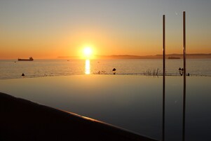 Um pôr do sol sobre águas calmas, com um cais que se estende na água.