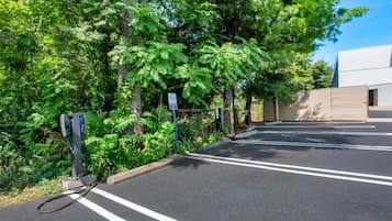 Uma área de estacionamento com estações de carregamento para veículos elétricos, uma via livre e um edifício com design moderno.