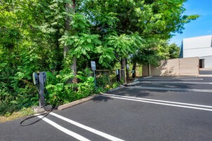 Uma área de estacionamento com estações de carregamento para veículos elétricos, uma via livre e um edifício com design moderno.