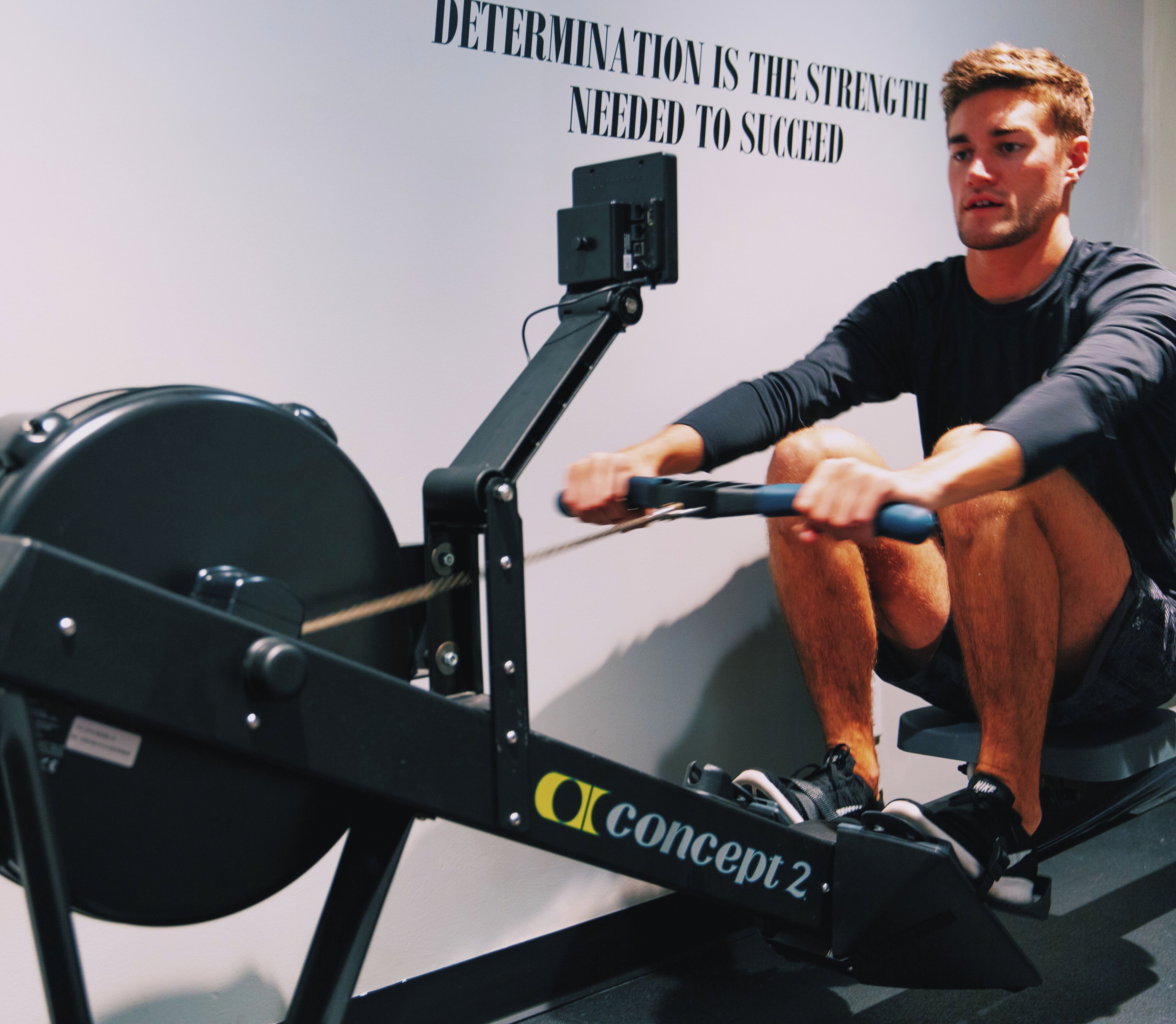 Uma bicicleta ergométrica com uma frase motivacional na parede ao fundo.