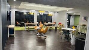 Um interior moderno com piso de madeira, várias mesas e cadeiras, e iluminação pendente.