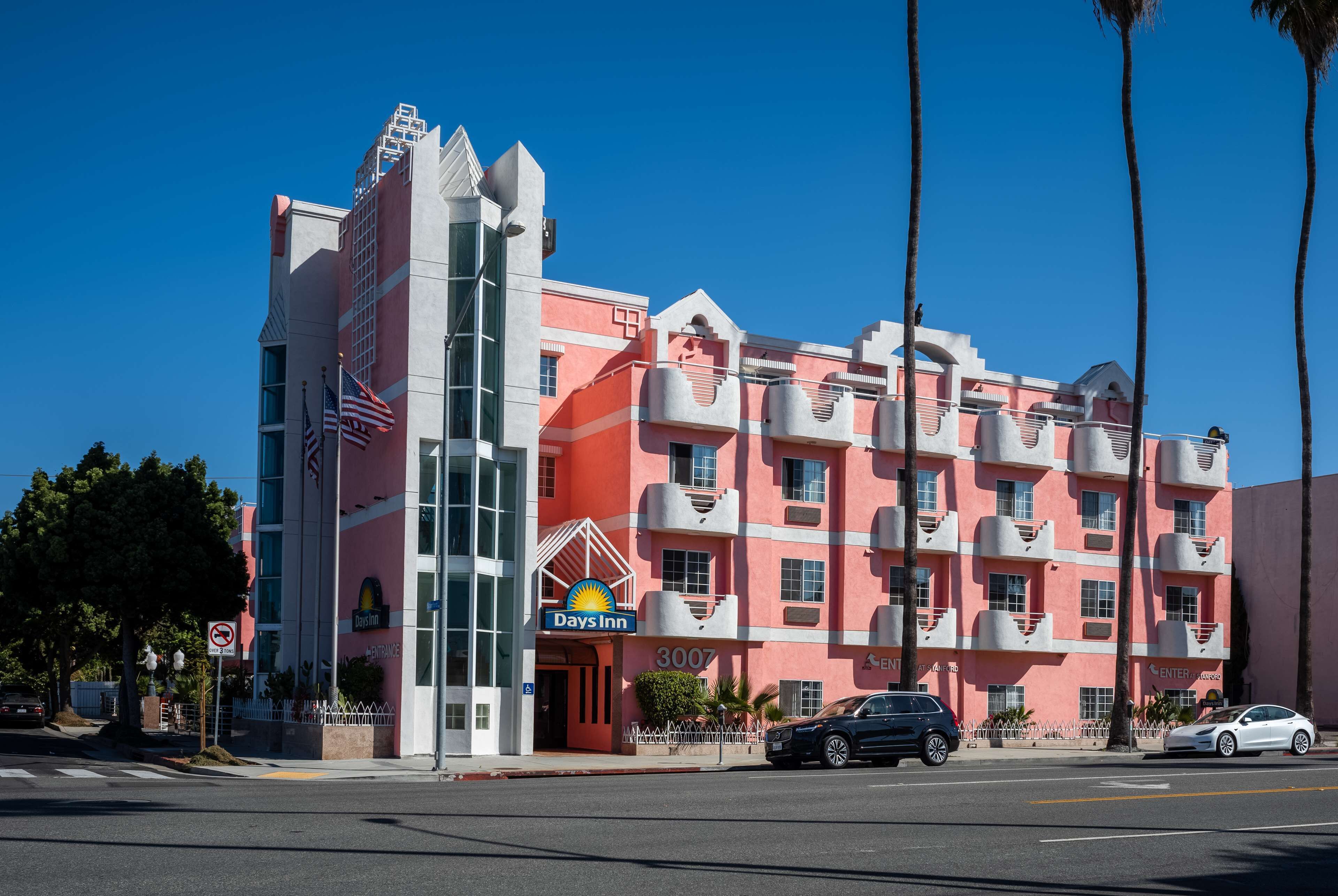 Um hotel rosa com um letreiro 'Days Inn', um letreiro 'McDonald's' e o número '3007'.