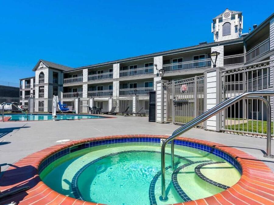 Um hotel com piscina, área de estar externa e um edifício de vários andares com varandas.