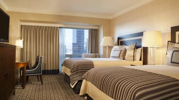 Quarto de hotel com duas camas, uma televisão, uma escrivaninha e uma cadeira.