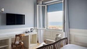 Quarto de hotel com escrivaninha, cadeira e cama.