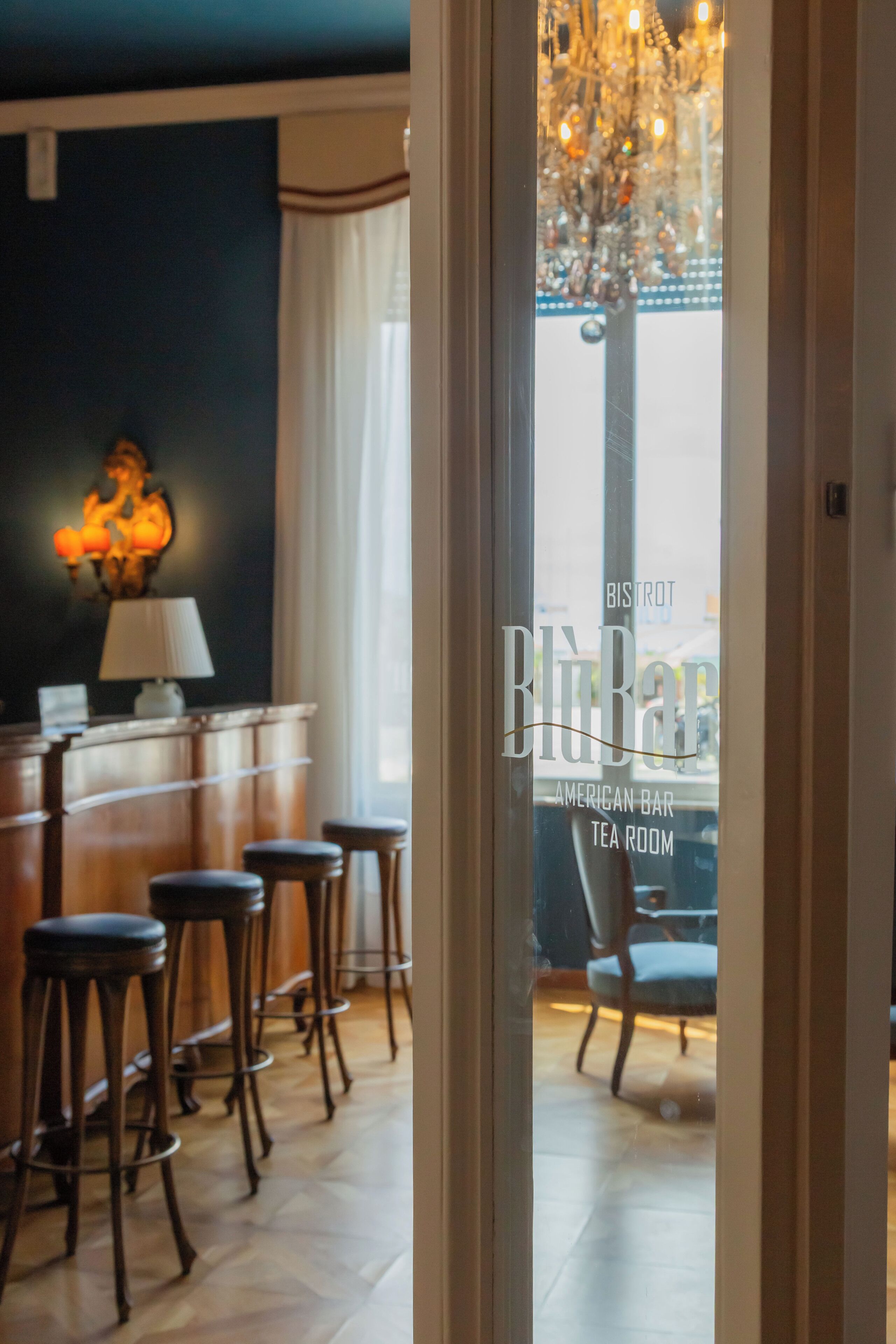 Uma área de bar com banquetas, balcão e lustre.
