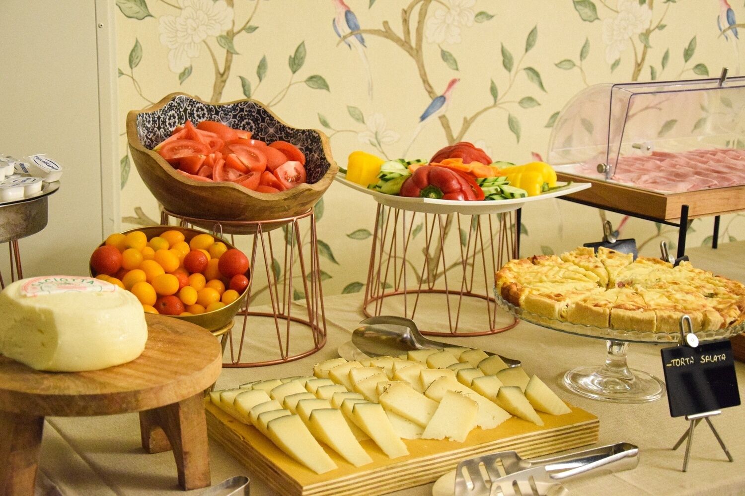 Buffet com diversos alimentos, incluindo queijo, frutas e pizza.