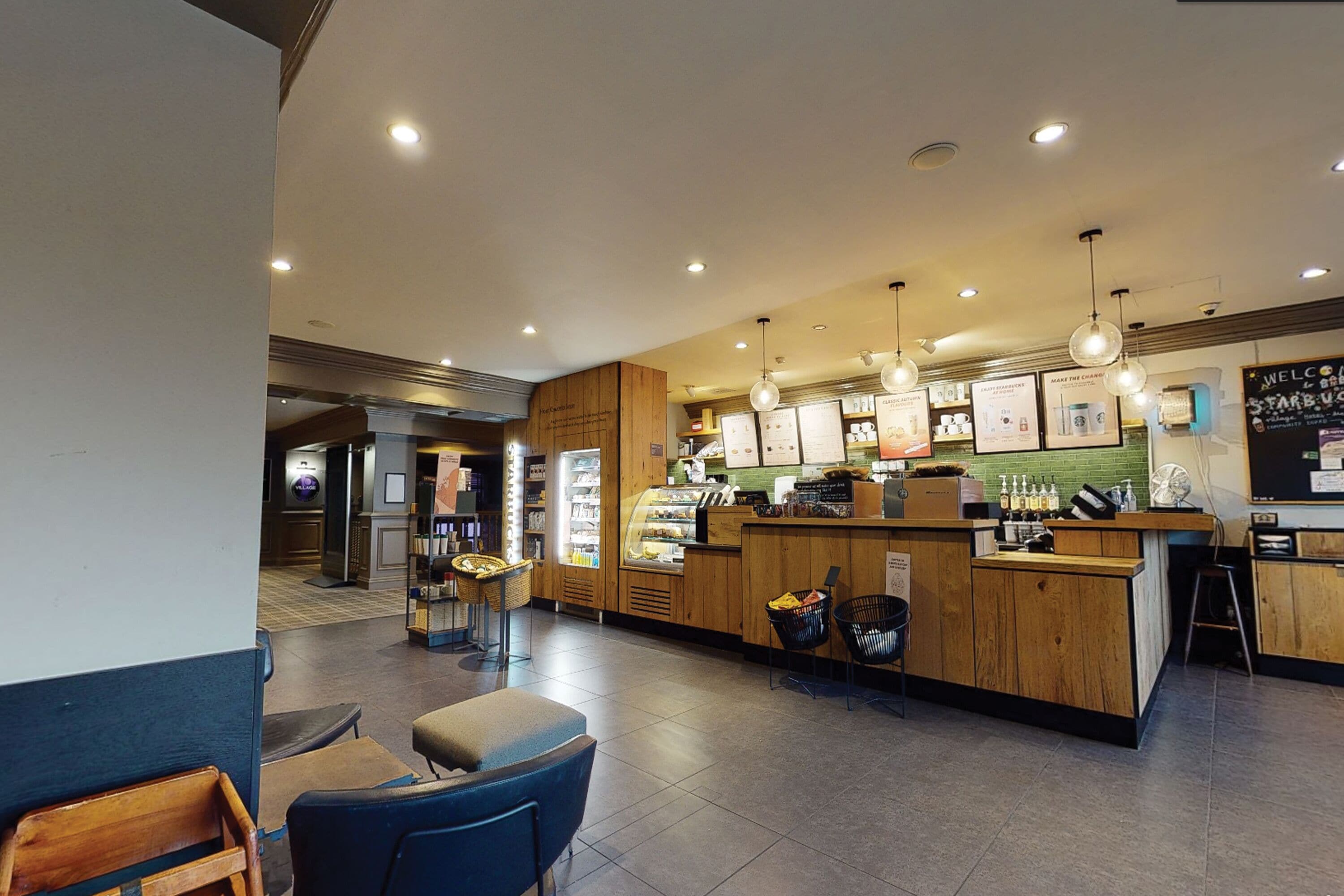 Interior moderno de uma cafeteria, com balcão, área de estar e cardápio visível.