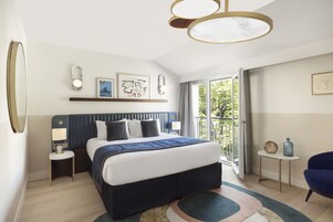 Quarto de hotel moderno com uma cama grande, uma mesa de cabeceira pequena, uma cadeira, varanda com vista e luminária no teto.