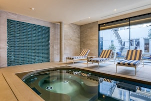 Uma área interna de piscina moderna com espreguiçadeiras e uma seção envidraçada.