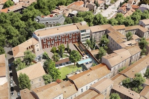Vista aérea de um complexo de edifícios com várias construções, piscina e vegetação ao redor.