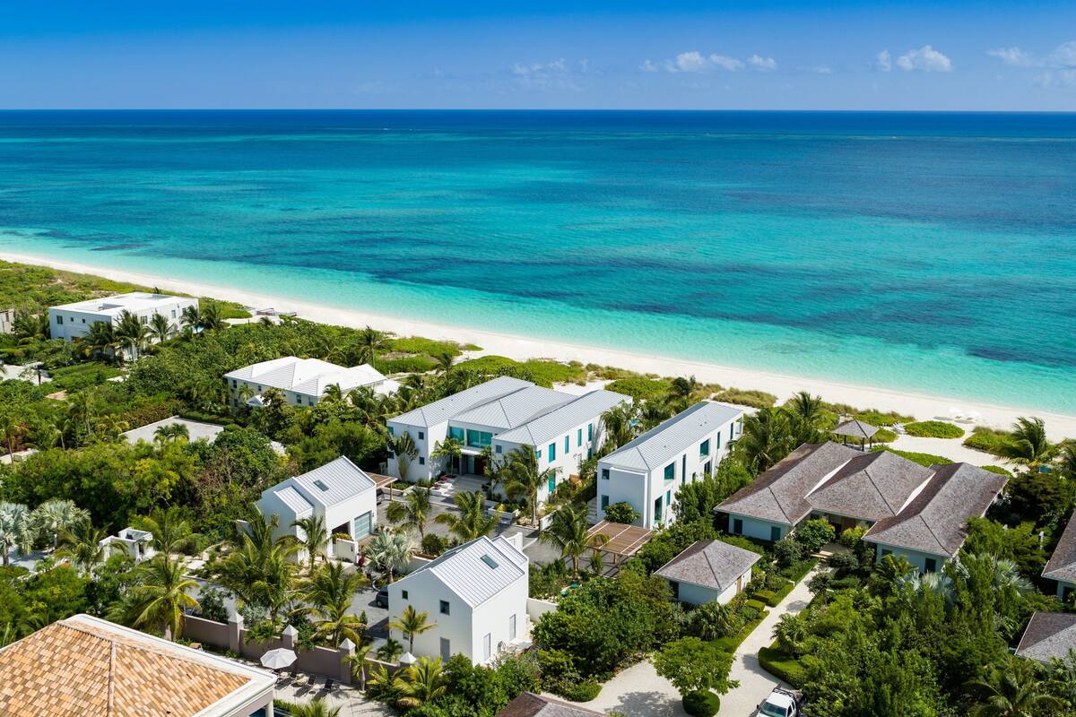 Uma área residencial costeira com casas, uma praia e águas azuis cristalinas.