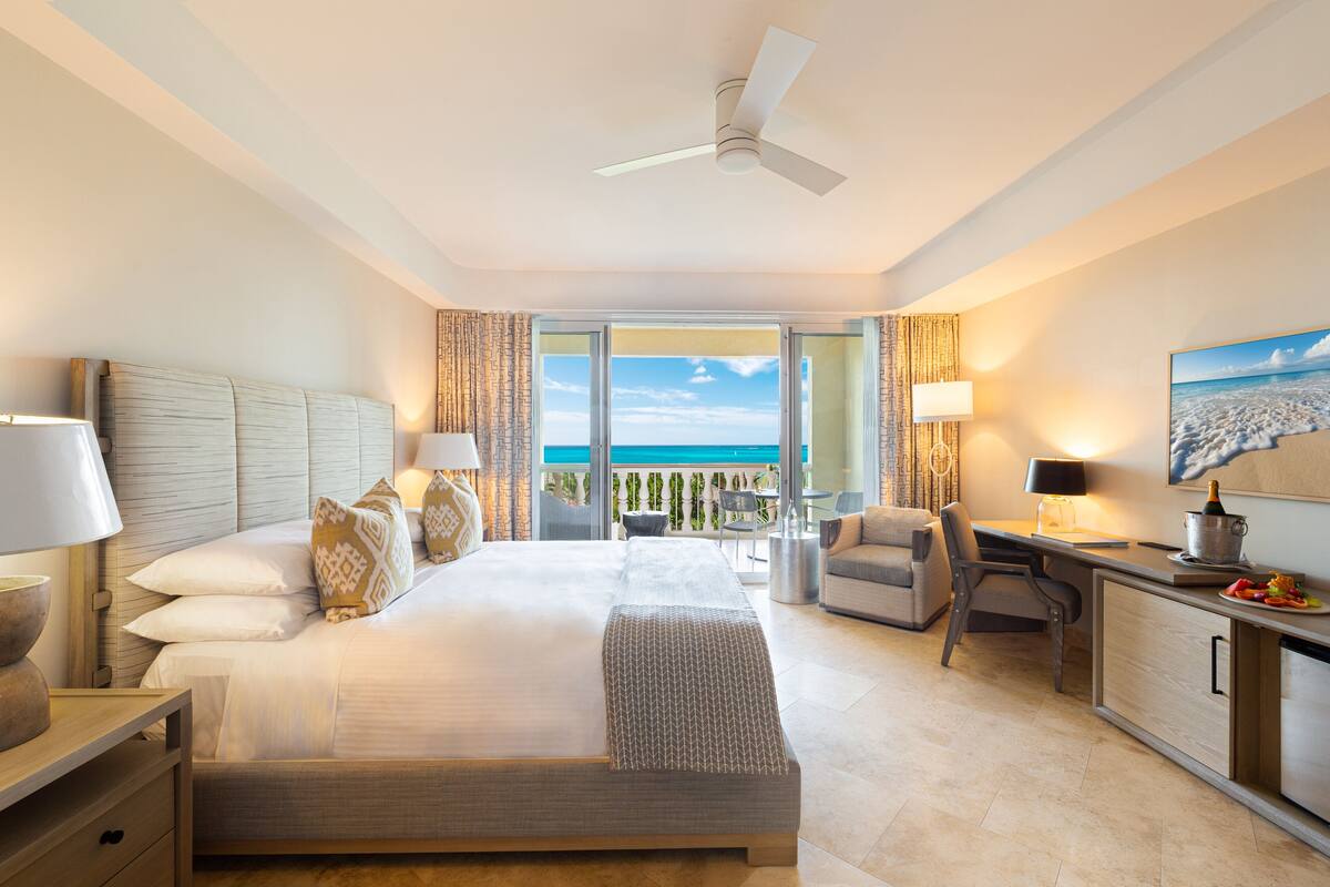 Quarto de hotel com cama, escrivaninha e vista para o oceano.
