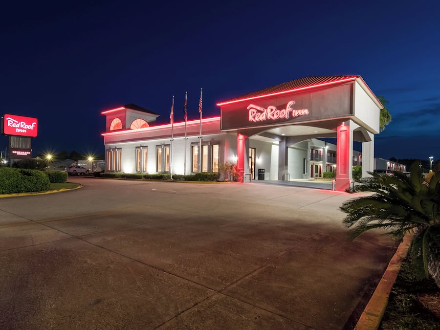Um Red Roof Inn com uma grande placa, estacionamento e entrada bem iluminada.