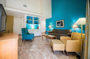 Uma sala de estar com parede azul, um sofá, uma poltrona, uma mesa de centro e uma televisão.