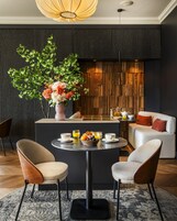Uma área de refeições moderna com uma mesa redonda, cadeiras e um vaso de flores.