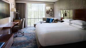 Quarto de hotel com uma cama grande, uma mesa com cadeira, uma mesinha e uma televisão.