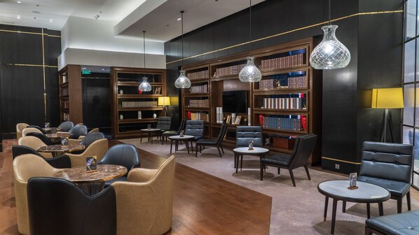 Uma biblioteca moderna com poltronas de couro, mesas e estantes.