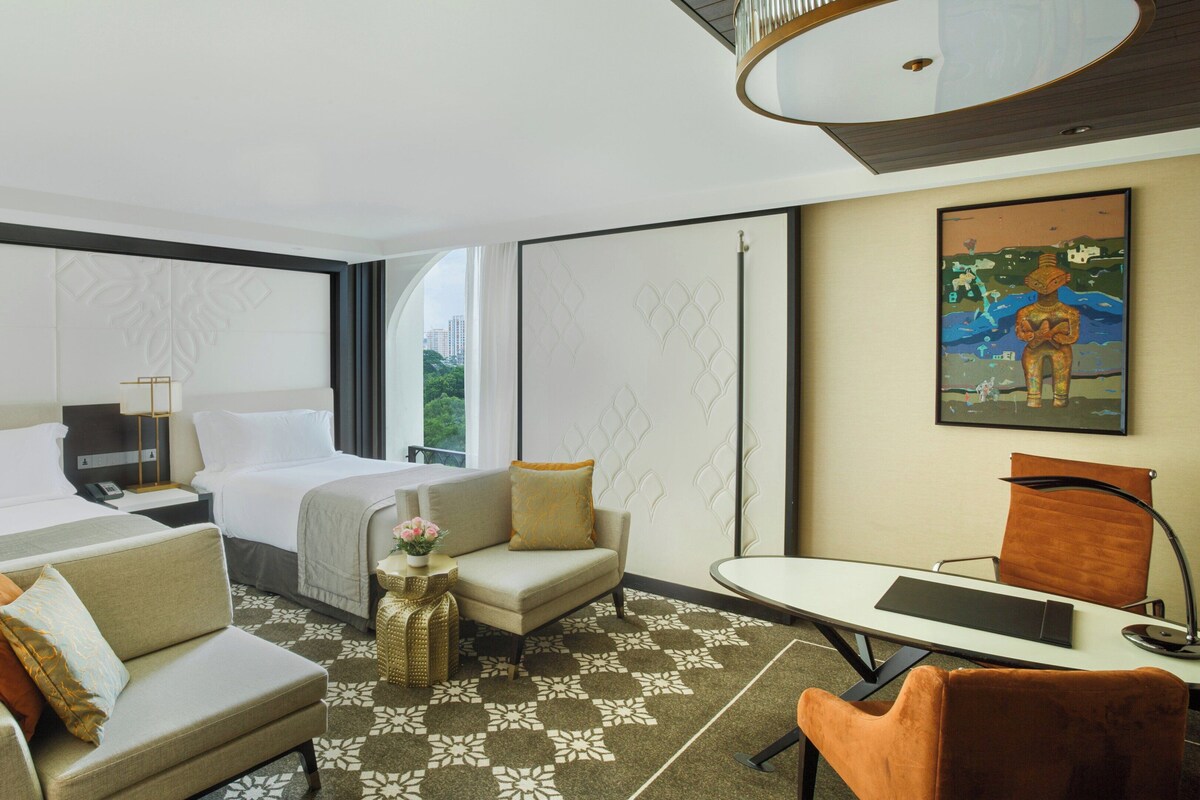 Quarto de hotel com cama, sofá, escrivaninha e cadeira.
