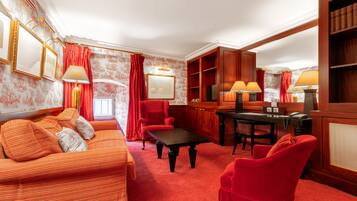 Quarto com sofá vermelho, poltrona vermelha, mesa de centro de madeira e estante de livros.