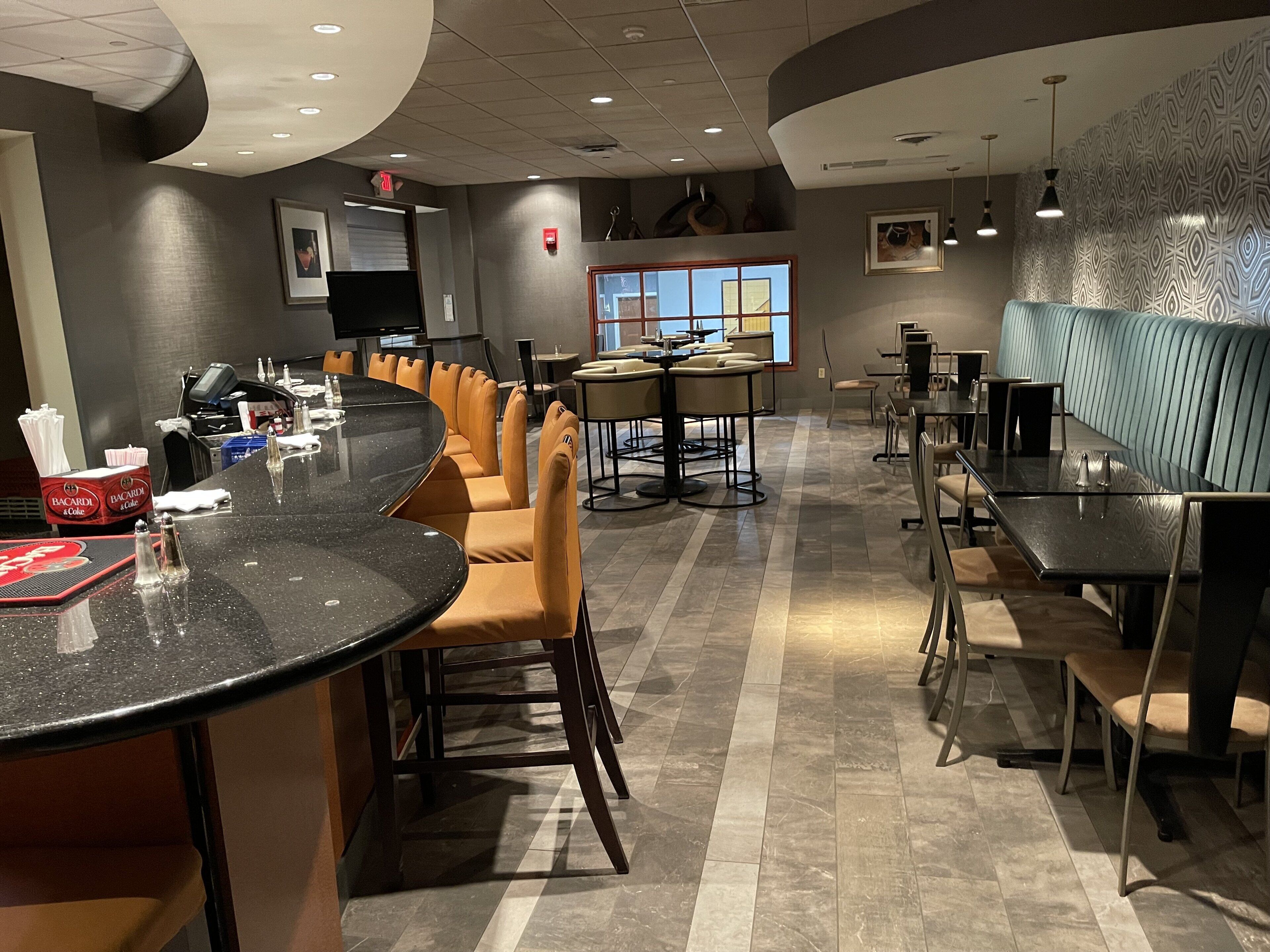 Um restaurante com área de bar, cabines e mesas.