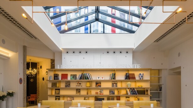 Uma biblioteca moderna com estantes, áreas de estar e um claraboia.