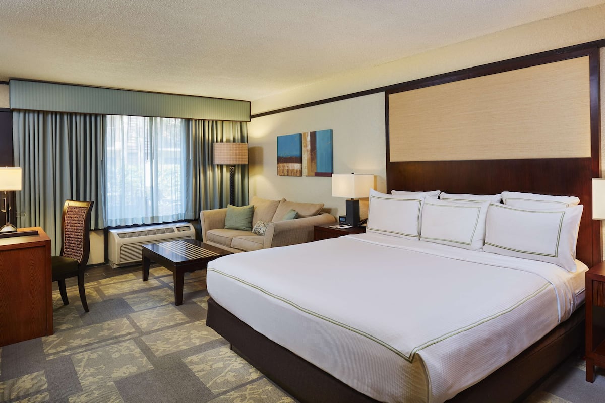 Quarto de hotel com uma cama grande, um sofá, uma mesa e uma cadeira.