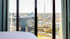 Quarto de hotel com uma janela grande, uma cama e cortinas.