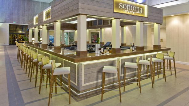 Uma área de bar com um letreiro que diz 'Sonoma', banquetas e um balcão.