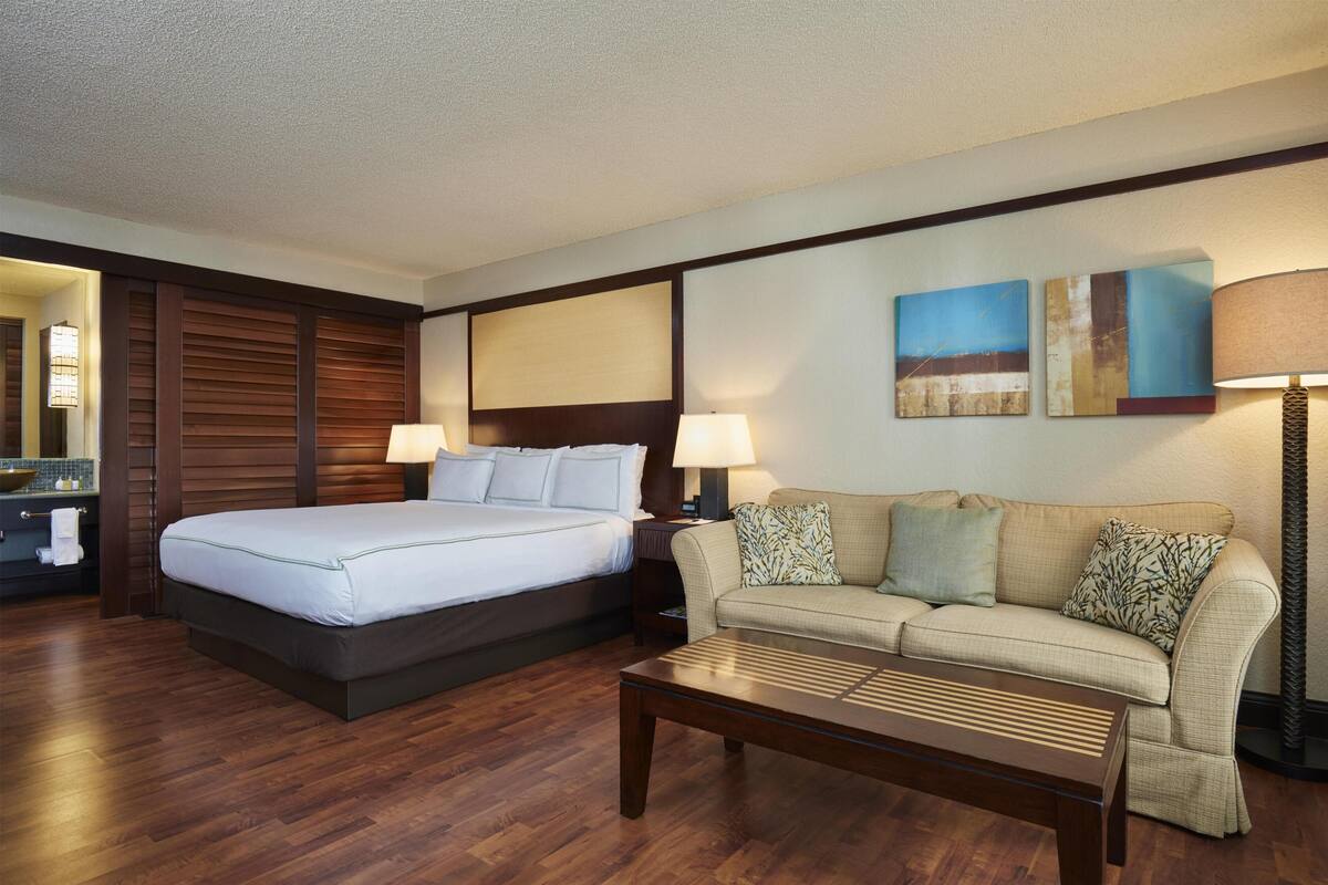 Quarto de hotel com uma cama, um sofá, uma mesa de centro e um abajur.