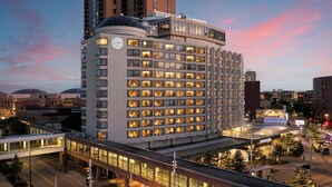 Um hotel com vários andares e design moderno, apresentando uma estrutura circular proeminente no canto superior esquerdo e uma placa Sheraton no andar térreo.