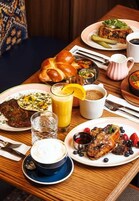 Uma mesa de café da manhã com diversos pratos, incluindo panquecas, ovos e uma xícara de café.