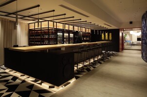 Uma área de bar moderna com um balcão comprido, vários bancos e piso estampado.