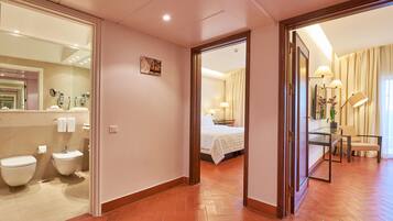 Quarto de hotel com banheiro, cama, escrivaninha e cadeira.