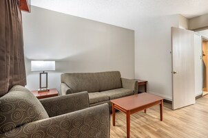 Uma sala de estar mobiliada com sofá, poltronas, mesa de centro e luminária.