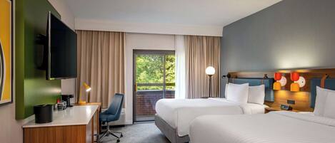 Quarto de hotel com duas camas, uma escrivaninha, uma cadeira, televisão e janela com cortinas.