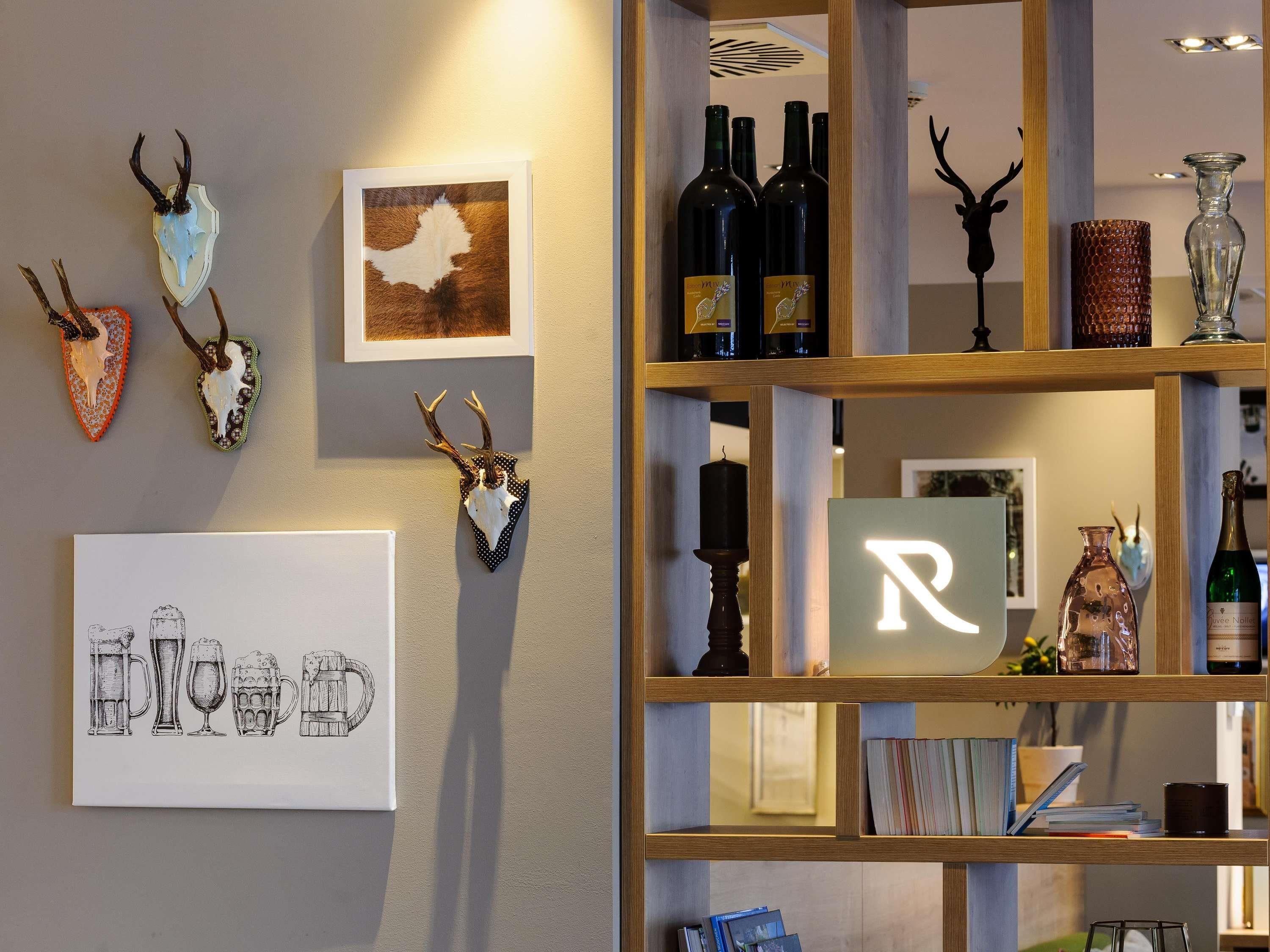 Paredes decoradas com caveiras de animais, uma obra de arte emoldurada e uma prateleira com garrafas de vinho e objetos decorativos.