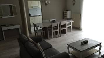 Uma sala de estar com sofá, mesa de centro e área de jantar com mesa e cadeiras.