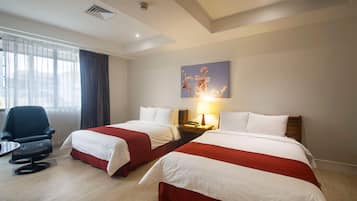 Quarto de hotel com duas camas, uma cadeira, uma mesa e um quadro na parede.