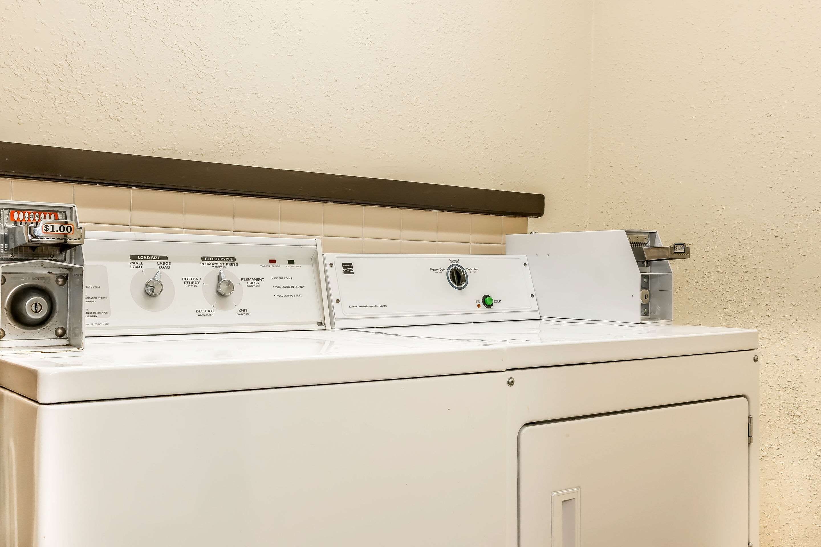 Vista frontal de uma máquina de lavar branca com painel de controle, etiqueta de preço e prateleira acima.