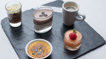 Uma bandeja com diversas sobremesas à base de chocolate e uma xícara de café sobre um tabuleiro de ardósia.