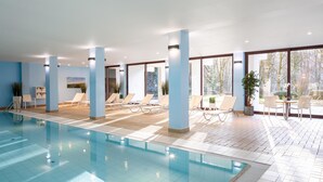Piscina com espreguiçadeiras e vista para árvores.