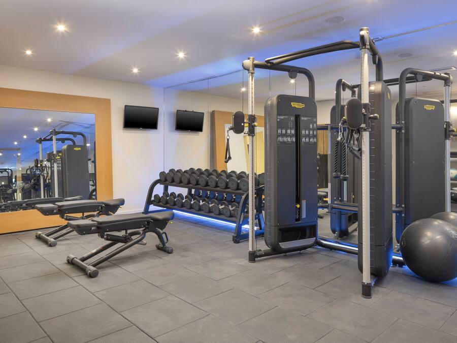 Uma academia com equipamentos de exercícios, halteres e bolas de ginástica.